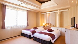 Quarto de hotel com duas camas, uma escrivaninha e uma televisão.