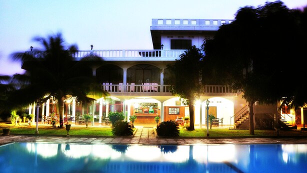 Um hotel com piscina, bar e área de estar coberta ao ar livre.