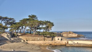 Uma área costeira com uma praia de areia, um muro de pedra e um pequeno edifício perto da água.