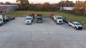 Um estacionamento com vários caminhões e um edifício ao fundo.