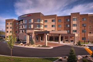 Um hotel Courtyard Marriott com design moderno, apresentando um pátio central, vários andares e um estacionamento.
