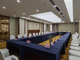 Uma sala de conferência com uma mesa comprida, cadeiras brancas e placas de identificação.