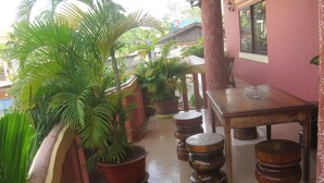 Um terraço com plantas em vasos, uma mesa de madeira e um chão de azulejos.