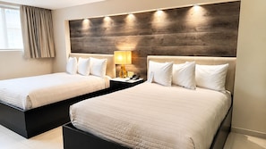 Quarto de hotel com duas camas, cabeceira de madeira, luminárias de apoio e uma janela com cortinas.