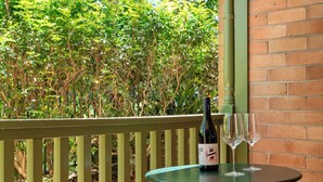 Uma varanda com uma mesa, uma garrafa de vinho e duas taças.