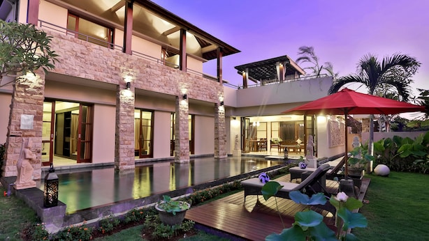 Uma casa moderna de dois andares com piscina, área de estar externa e um jardim bem cuidado.