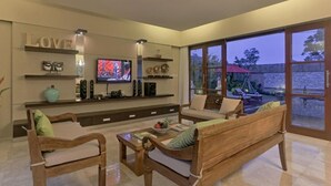 Uma sala de estar ampla, com uma televisão grande, assentos confortáveis e vista para o exterior.