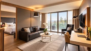 Quarto de hotel moderno com cama, sofá, mesa de jantar e televisão.