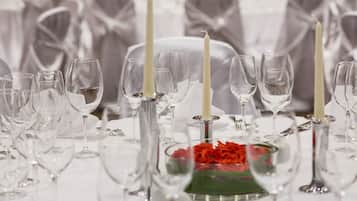 Mesa posta para um evento formal, com vários copos de vinho e velas.