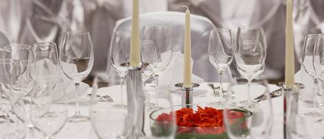Mesa posta para um evento formal, com vários copos de vinho e velas.