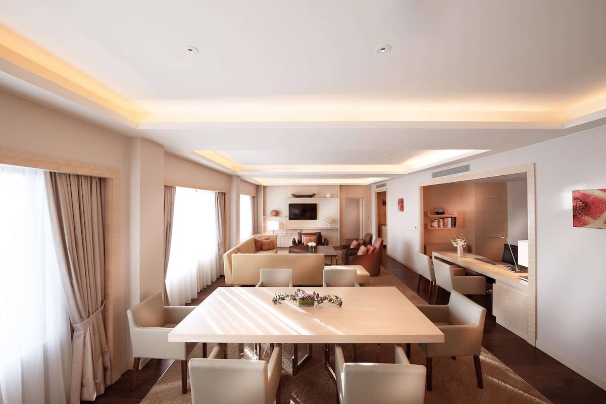 Quarto de hotel moderno com área de jantar, sala de estar e cozinha compacta.