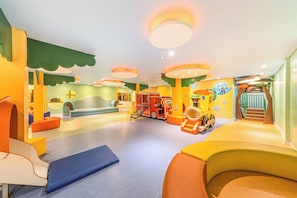 Uma área de recreação infantil com móveis coloridos, um escorregador e uma casinha.