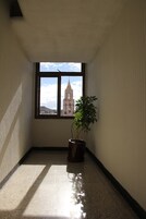 Um corredor estreito com uma planta em vaso e uma janela com vista para uma catedral.