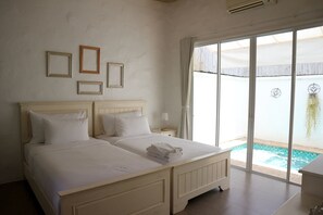 Quarto com duas camas, vista para uma piscina e porta de correr para o exterior.