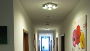 Um corredor de hotel com carpete estampado, portas de madeira e um quadro na parede.