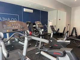 Uma academia com diversos equipamentos de exercícios, incluindo esteiras, um banco de musculação e halteres.