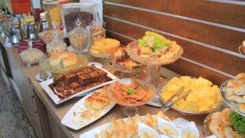 Buffet com diversos pratos, incluindo saladas, pães e sobremesas.