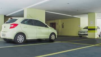 Garagem de estacionamento com um carro branco estacionado numa vaga designada.