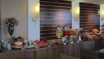Disposição de buffet com diversos alimentos e dispensadores de bebidas.
