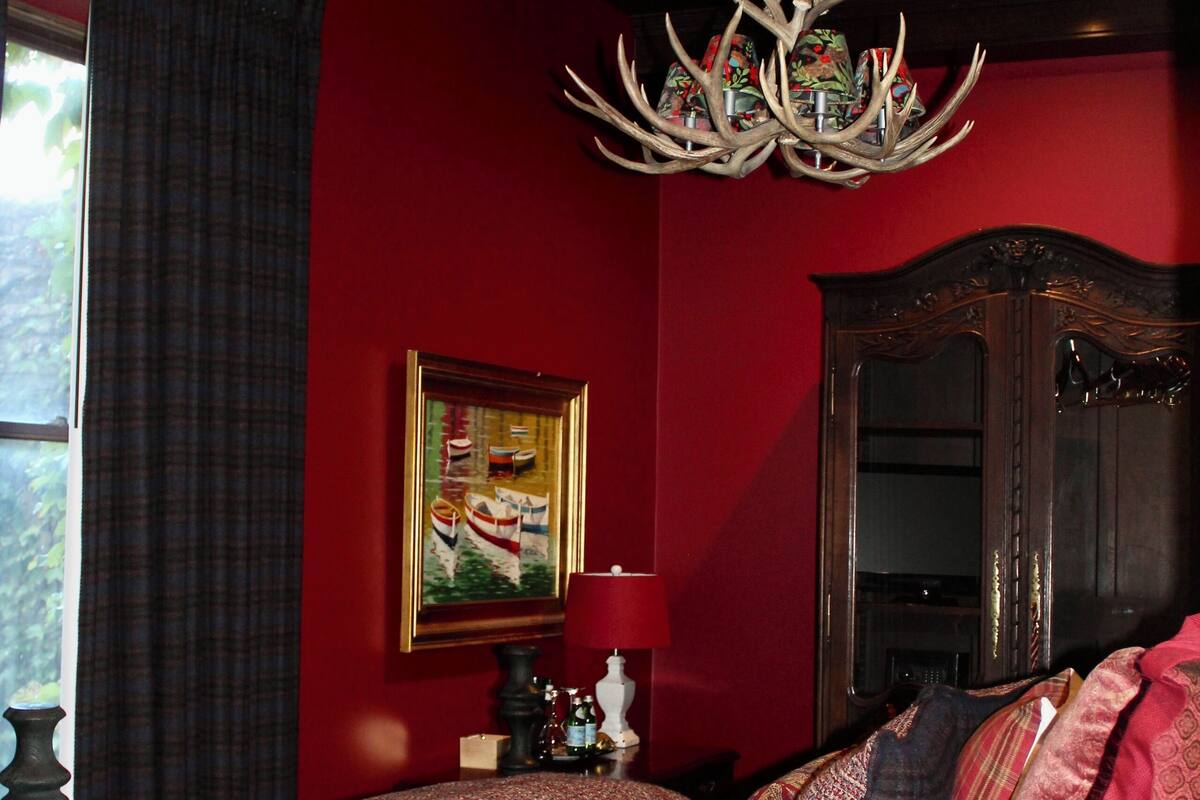 Quarto com uma cama grande, um candelabro, um quadro e um espelho.