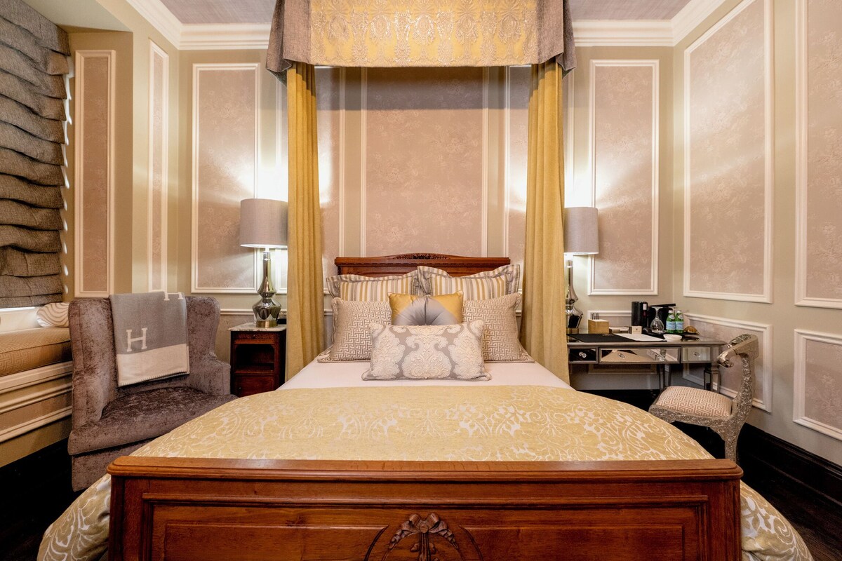 Quarto de hotel espaçoso com uma cama grande, uma escrivaninha e uma cadeira.