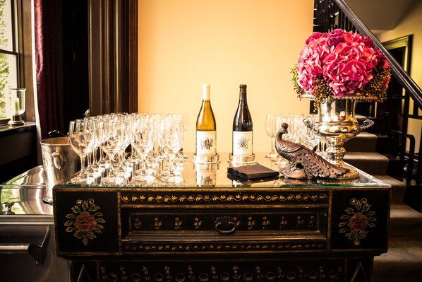 Uma mesa com garrafas de vinho, copos e um vaso decorativo com flores.