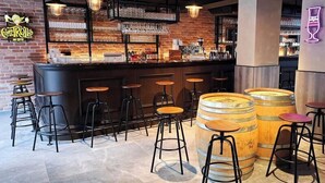 Uma área de bar com banquetas de madeira, parede de tijolos e um letreiro de neon.