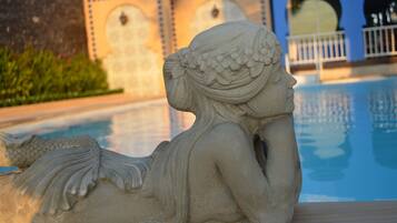 Escultura de pedra de uma sereia perto de uma piscina.