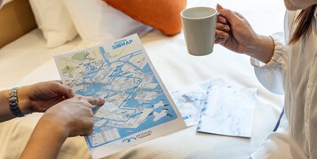 Uma pessoa segurando um mapa e uma caneca, enquanto outra pessoa aponta para o mapa.
