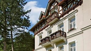 Um edifício com vários andares, varanda e um gramado bem cuidado com cadeiras de descanso.