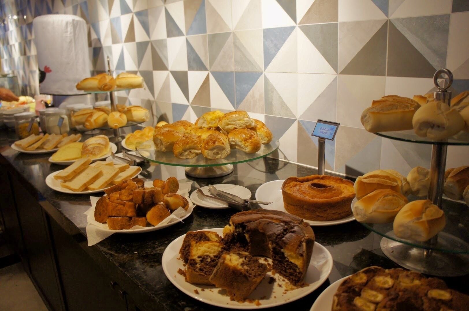 Um buffet com diversos pães e doces.