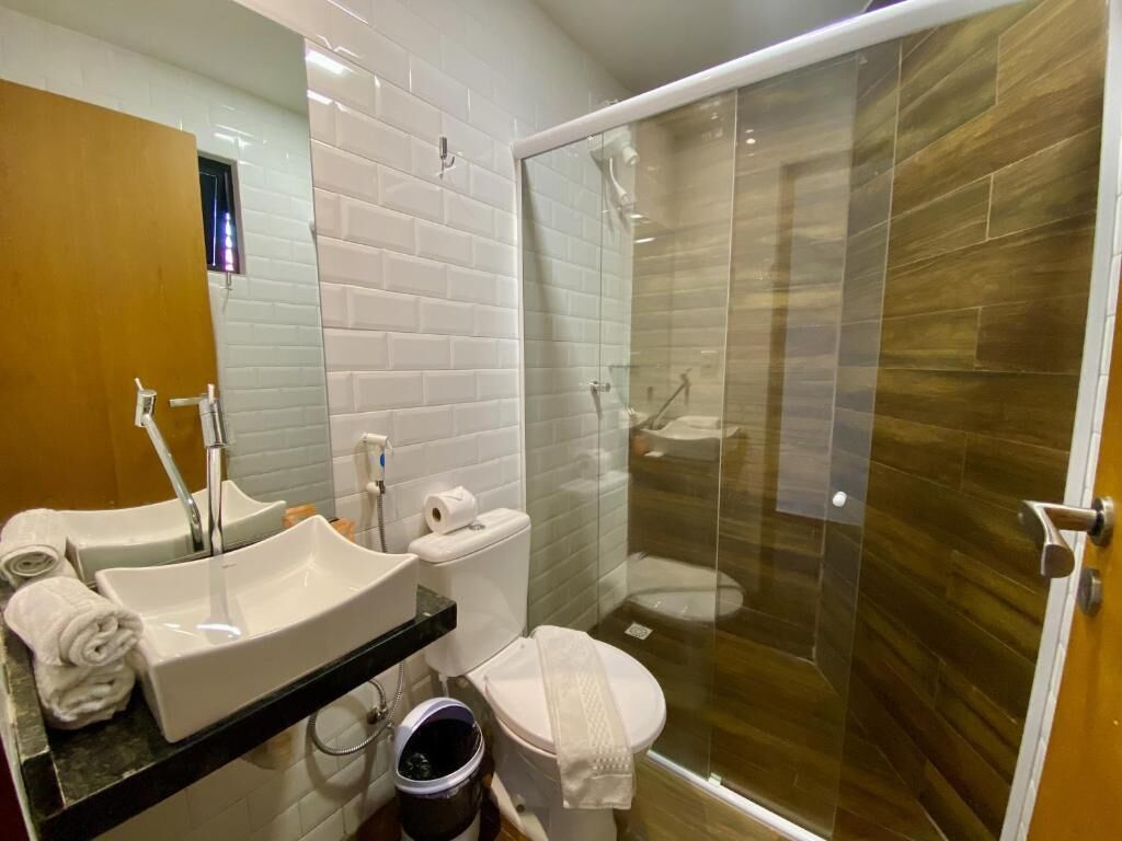 Uma casa de banho moderna com chuveiro em cabine de vidro, toucador com duas pias e sanita.