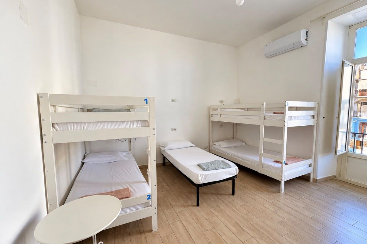 Quarto com beliches, uma mesinha e janela com vista.