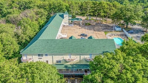 Um edifício grande com telhado verde, várias varandas e uma piscina.