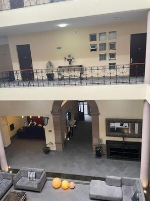 Um hall de hotel amplo, com vários níveis, balcão de recepção, área de estar e lareira.