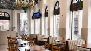 A restaurant interior with booths and tables, a chandelier, and a TV screen.