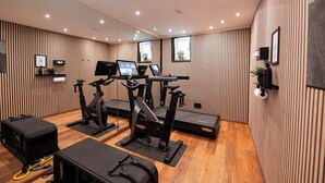 Uma sala de ginástica com equipamentos de exercício, paredes de madeira e janelas grandes.