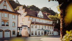 Um hotel europeu tradicional com fachada clássica, várias janelas e uma placa indicando que se trata de um hotel.