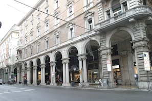 Um edifício histórico com várias abóbadas e colunas, com lojas e uma entrada para pedestres.