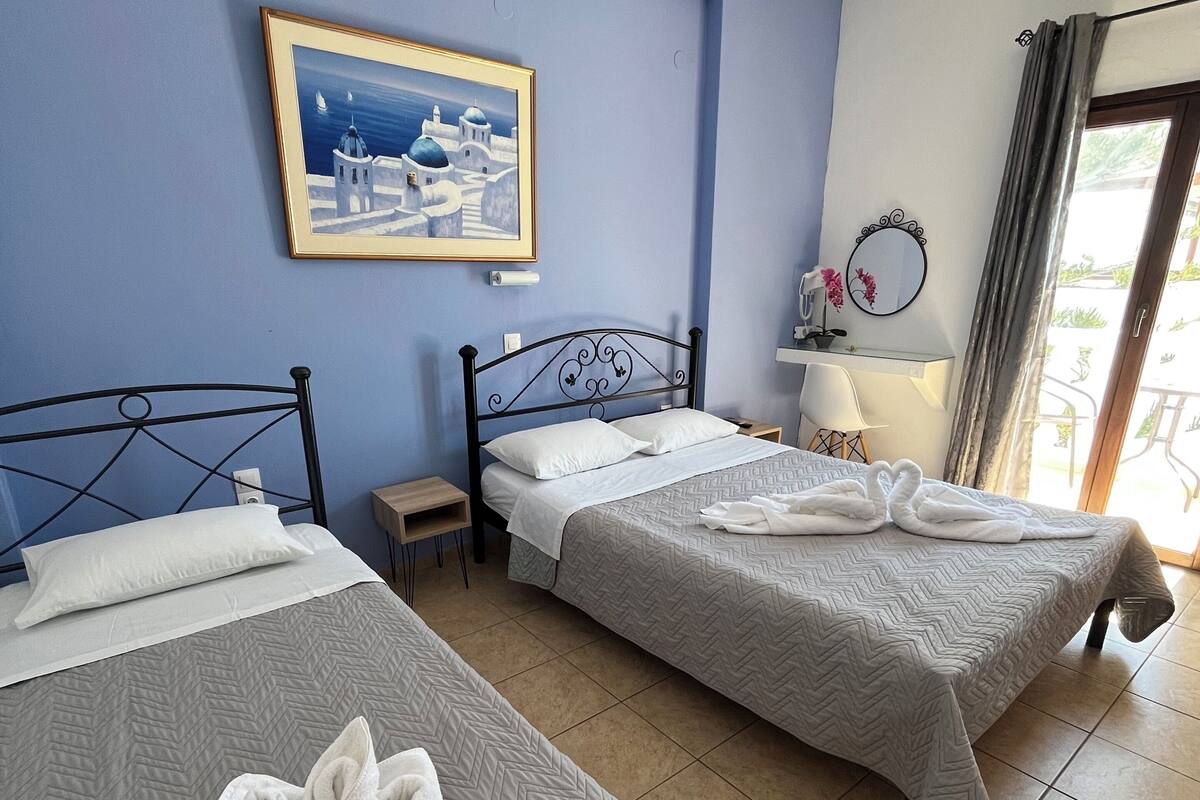 Quarto de hotel com duas camas, um quadro, um espelho e vista para o exterior.