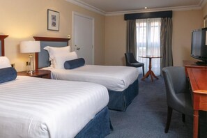 Quarto de hotel com duas camas, televisão, escrivaninha e uma cadeira.