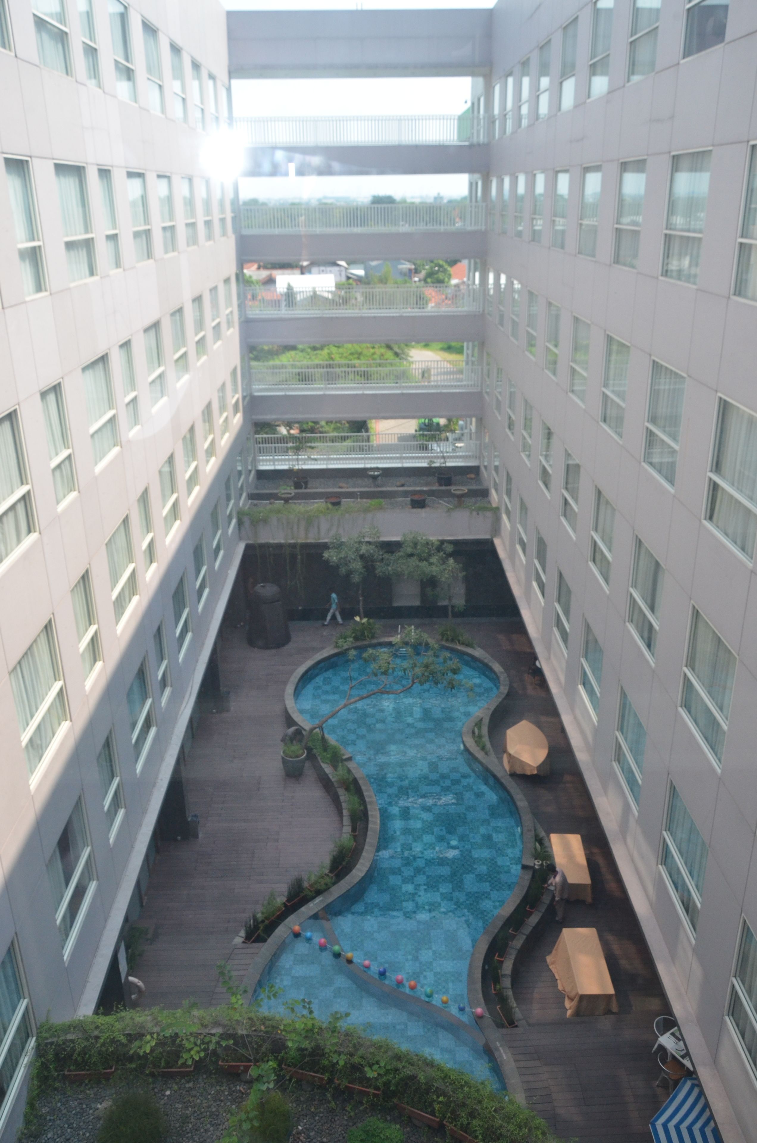 Um edifício com vários níveis, piscina central, varandas e áreas de estar ao ar livre.