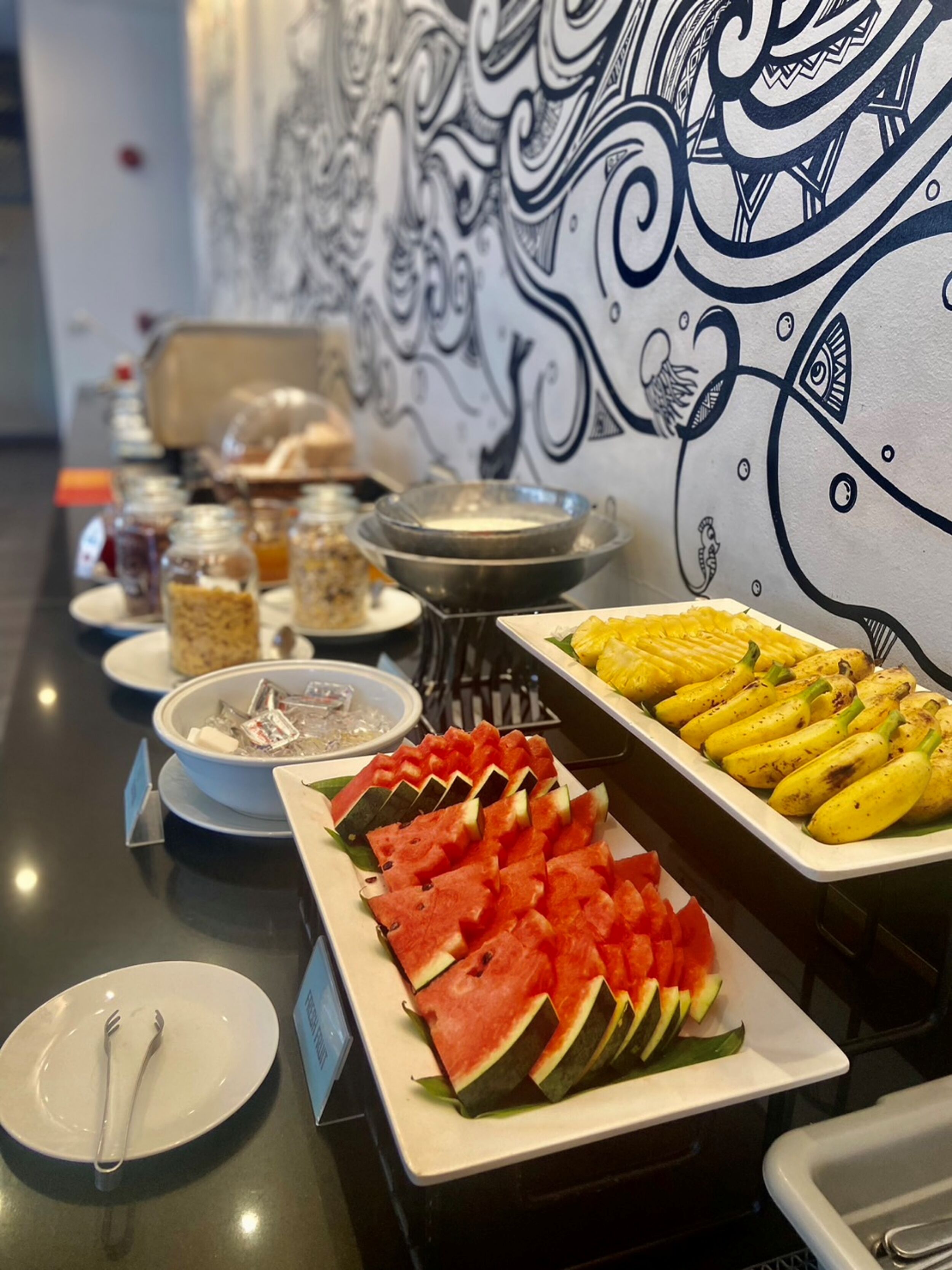 Buffet com melancia, bananas e outras frutas.