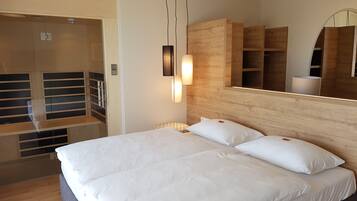 Quarto de hotel com cama grande, cabeceira de madeira, espelho e armário embutido com várias prateleiras.