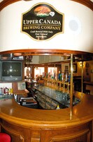 Uma área de bar com um letreiro da Upper Canada Brewing Company, uma televisão e diversas torneiras de cerveja.