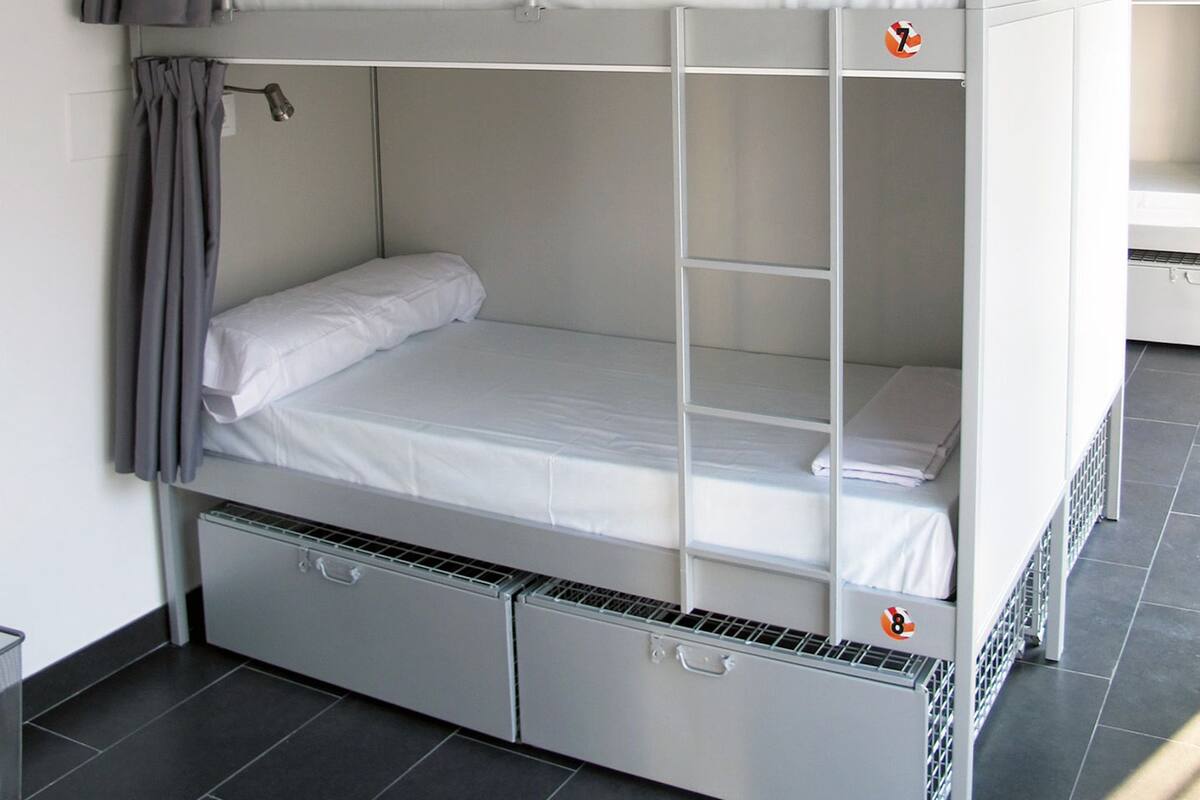 Uma cama beliche com escada, uma gavetinha e uma prateleira.