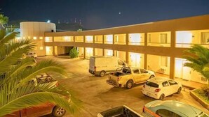 Um motel de vários andares com um estacionamento que contém vários veículos.