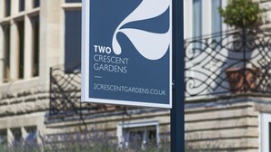 Placa com o nome 'Two Crescent Gardens' e um endereço URL.