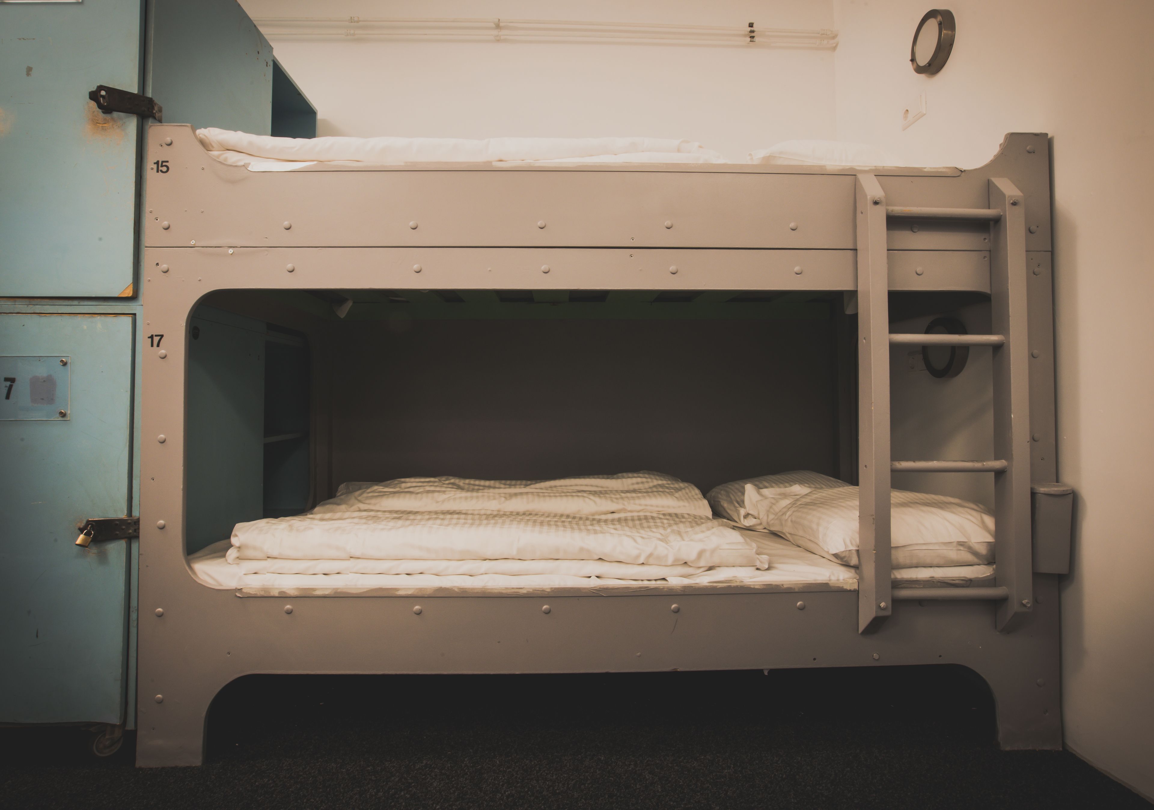 Uma cama beliche com escada, uma prateleira pequena e uma porta com fechadura.