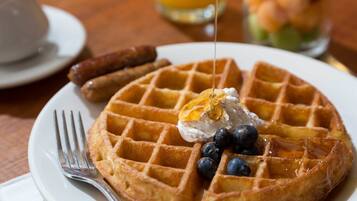Um prato com um waffle, mirtilos e xarope.